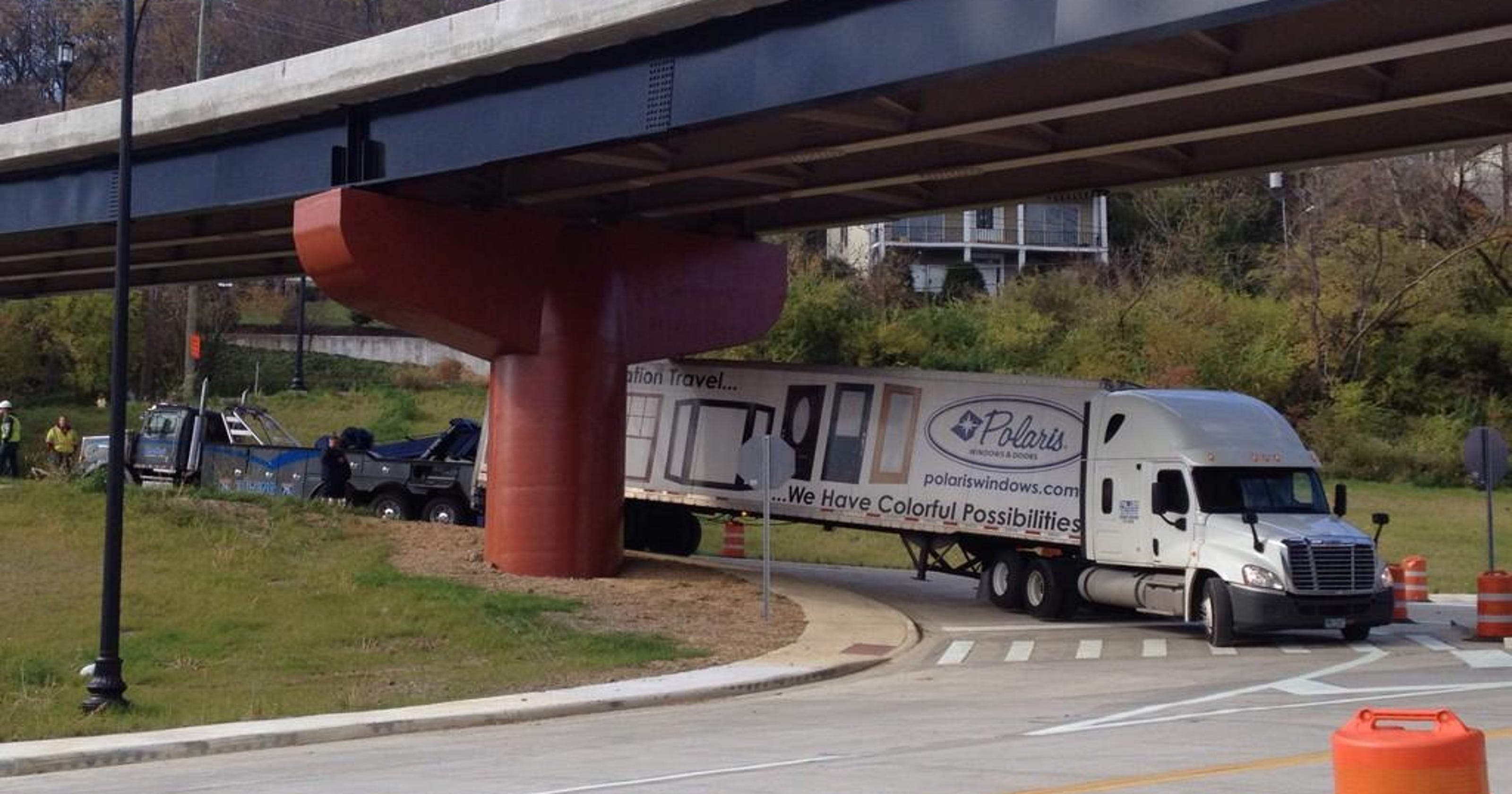 Car strikes building, semi stuck under bridge